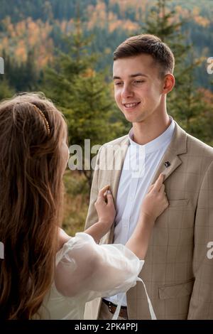 The bride looks at the groom with loving eyes. Smiling newlyweds look ...