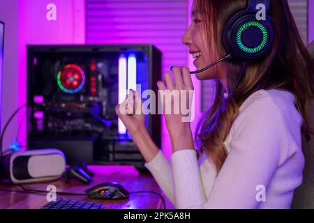 Young Asian female gamer playing video game with controller relaxing on ...