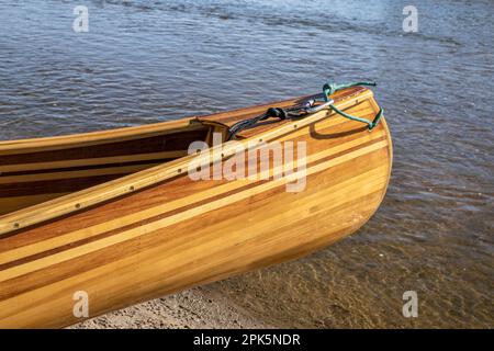 a bow of beautiful, home built, wooden canoe on a river shore Stock ...