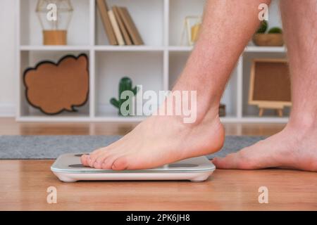 Man weighing himself - male bare feet stepping on white digital floor ...
