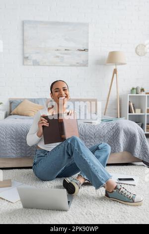 Pleased woman sitting near devices and coffee on table at home,stock ...