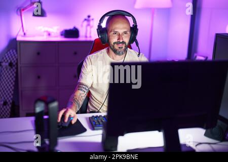 Young bald man streamer playing video game using computer at gaming ...