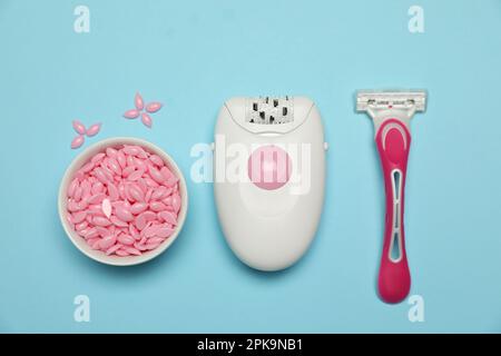 Modern epilator, wax beads and razor on light grey background, flat lay ...
