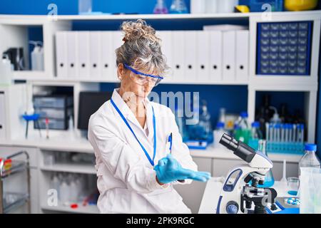 Middle age woman wearing scientist uniform watching embryo on touchpad ...
