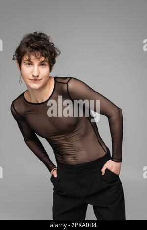 bigender person in black transparent top leaning on stylish partner ...