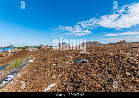 Soil compactors moving around and manipulating trash in the dirt on a ...