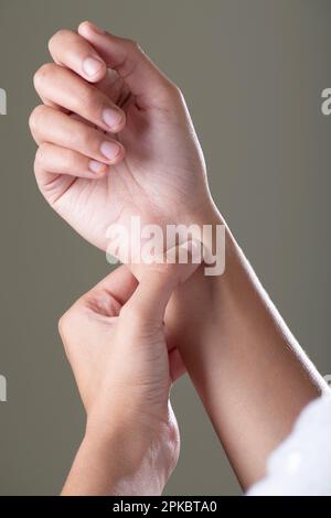 Female hand self checking pulse rate on grey background Stock Photo - Alamy