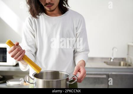 Man trying to boil pasta Stock Photo - Alamy