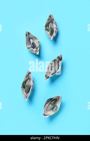 Origami boats made of dollar banknotes on blue background, closeup ...