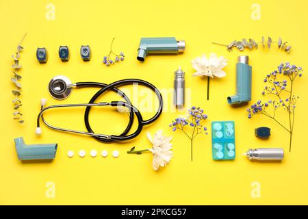 Asthma inhalers with stethoscope, pills and flowers on yellow ...