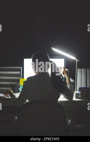 Back view of a woman working overtime Stock Photo - Alamy