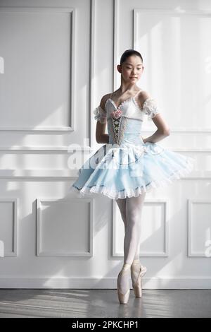Ballerina in ballet shoes. Asian girlÂ tying ribbons of toe shoes ...