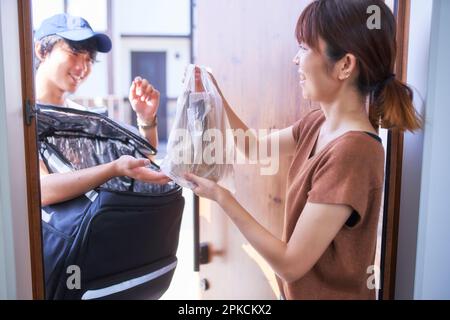 Woman receiving items from food delivery man Stock Photo - Alamy