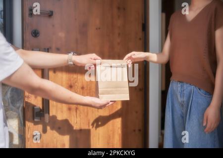 Woman receiving items from food delivery delivery man Stock Photo - Alamy