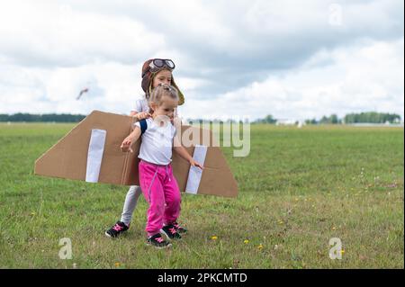 Little girls in a pilot's costume are hugging outdoors. Two sisters ...
