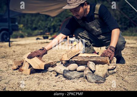 Man placing firewood in fire pit Stock Photo - Alamy