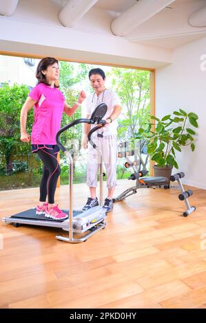 A middle-aged couple exercising with a machine at their own home Stock ...
