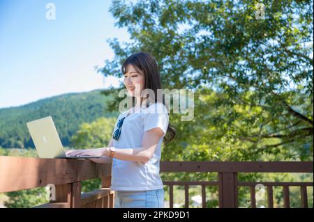 Woman working remotely from a log cabin balcony Stock Photo - Alamy