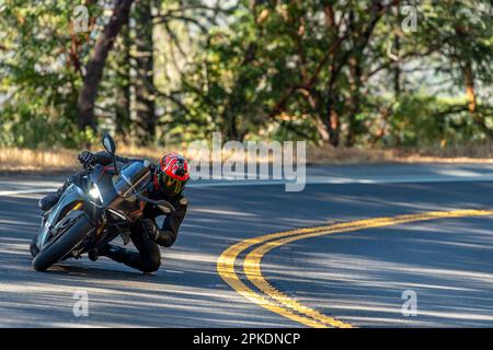 A person riding a motorcycle down a winding road Stock Photo - Alamy