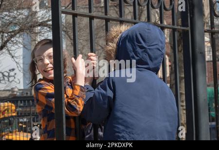 A Hasidic Jewish boy enjoys swinging on a fence door during recess from ...
