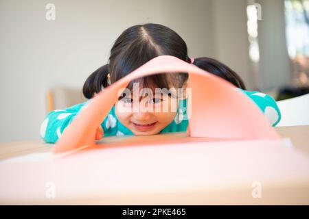Girl peeking through a gap in the drawing paper Stock Photo - Alamy