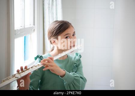 Girl playing flute by the window Stock Photo - Alamy