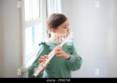 Girl playing flute by the window Stock Photo - Alamy