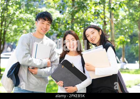 Three students holding notebooks and laughing Stock Photo - Alamy