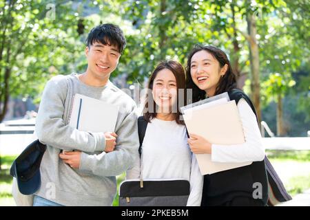 Three students holding notebooks and laughing Stock Photo - Alamy