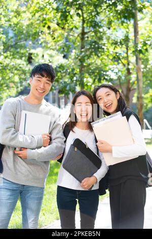 Three students holding notebooks and laughing Stock Photo - Alamy