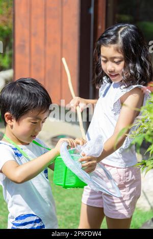 Sister and brother catching insects Stock Photo - Alamy