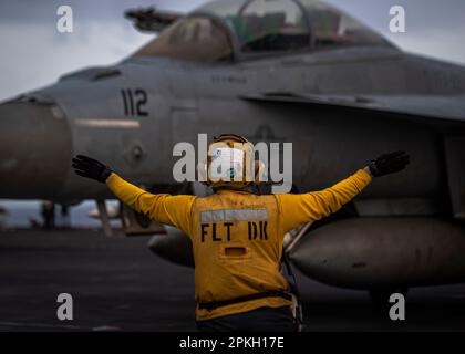 230406-N-MH015-2035 EAST CHINA SEA (April 6, 2023) A U.S. Navy Sailor directs an F/A-18F Super ...