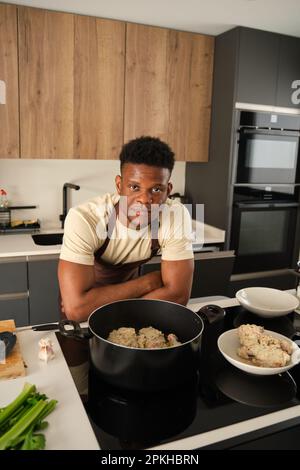 Young black man preparing fried chicken mince with vegetables recipe in ...