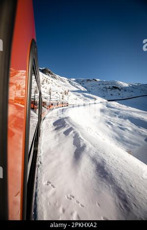 A red mountain train goes up a mountain in winter,Gornergrat in Zermatt ...