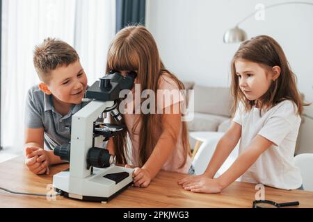 Using microscope. Kids having fun in the domestic room at daytime ...