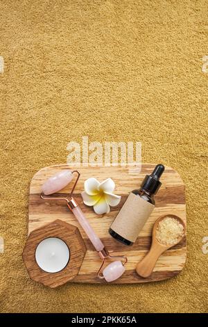 Wooden tray with bottle of face serum and leaves on grey marble table ...