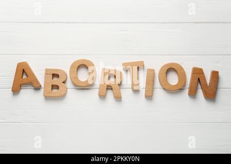 Word Abortion made of wooden letters on light grey background, flat lay ...