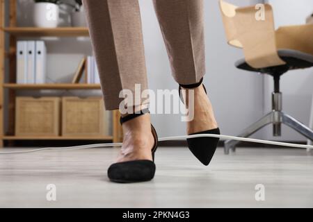 Woman tripping over cord in office, closeup Stock Photo - Alamy