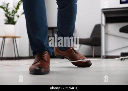 Man tripping over cord in office, closeup Stock Photo - Alamy