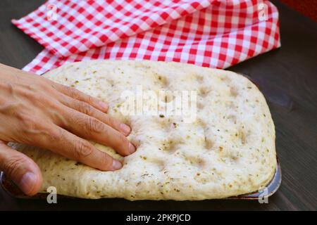 Creating dimples in the dough with fingertips for baking Italian ...
