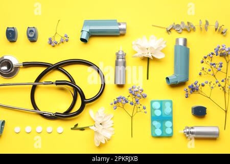 Asthma inhalers with stethoscope, pills and flowers on yellow ...