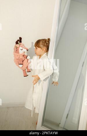 A girl in a dressing gown plays in bed with knitted toys Stock Photo ...