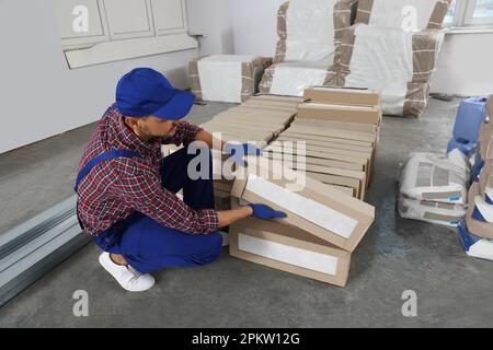 Construction worker with packed new boxes in room prepared for ...