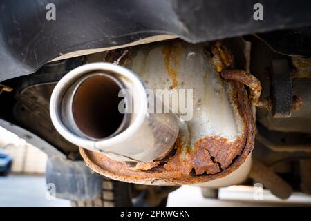 Rusty car exhaust muffler with a through hole, close-up. Corrosion on a ...
