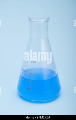 Graduated flat bottomed lab flask with blue fluid chemical solution and ...