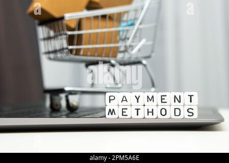 Payment methods words on cubes laying on the laptop and a toy shopping ...