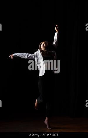brunette actress dances barefoot in the rehearsal hall of the theater ...