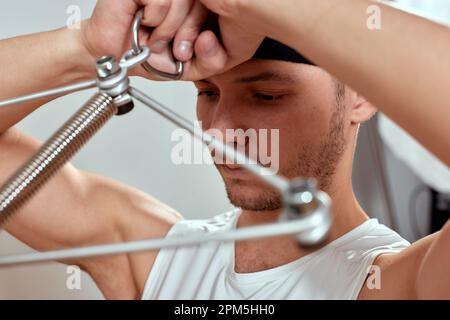 A man does exercises for the neck on reformers during Pilates, a young ...