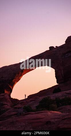 Man standing under natural arch on Cathedrals beach in Galicia, Spainn ...