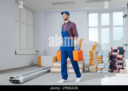 Construction worker carrying canisters in room prepared for renovation ...